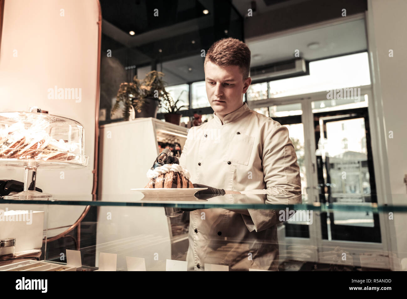 In the kitchen. Nice pleasant pastry chef wearing his uniform while ...