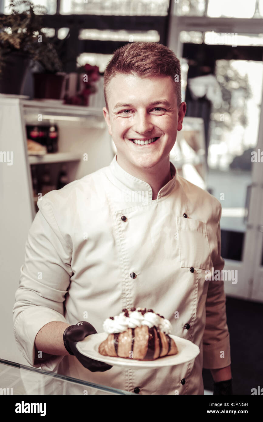 Professional pastry chef. Happy nice man holding a plate with a ...