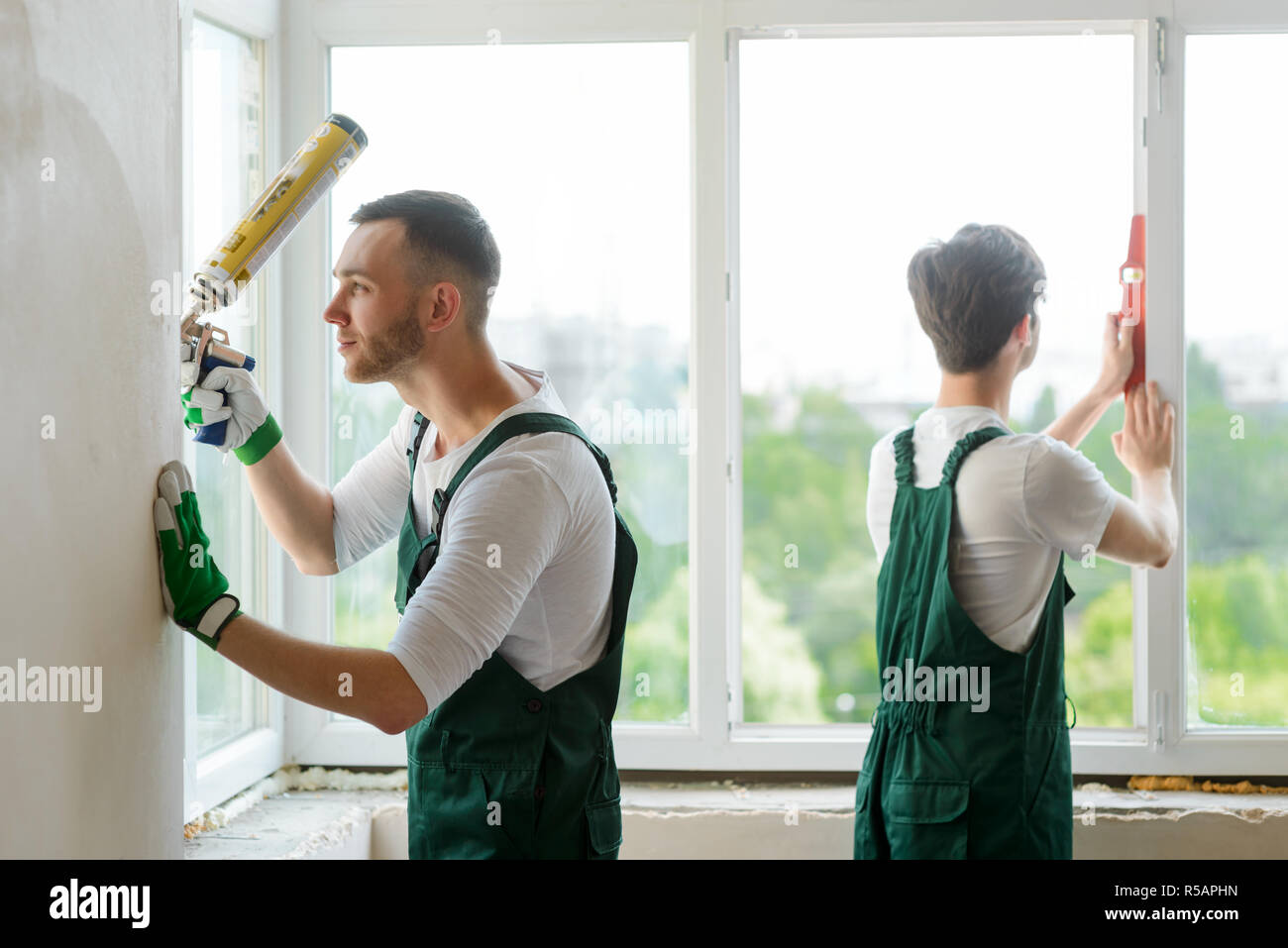Two workers installing a window Stock Photo - Alamy