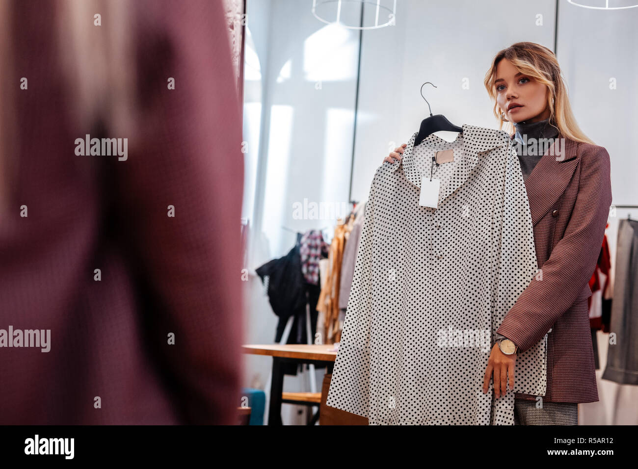 Spotted dress. Blonde-haired stylish appealing woman looking at white ...