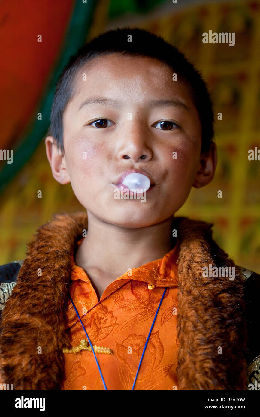 Young buddhist monk blowing bubble gum at monastery, nr Xinlong ...