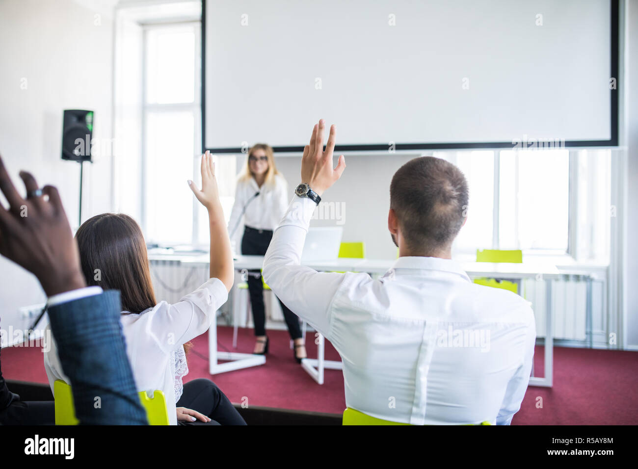 Audience raising hands up while businesswoman is speaking in training ...
