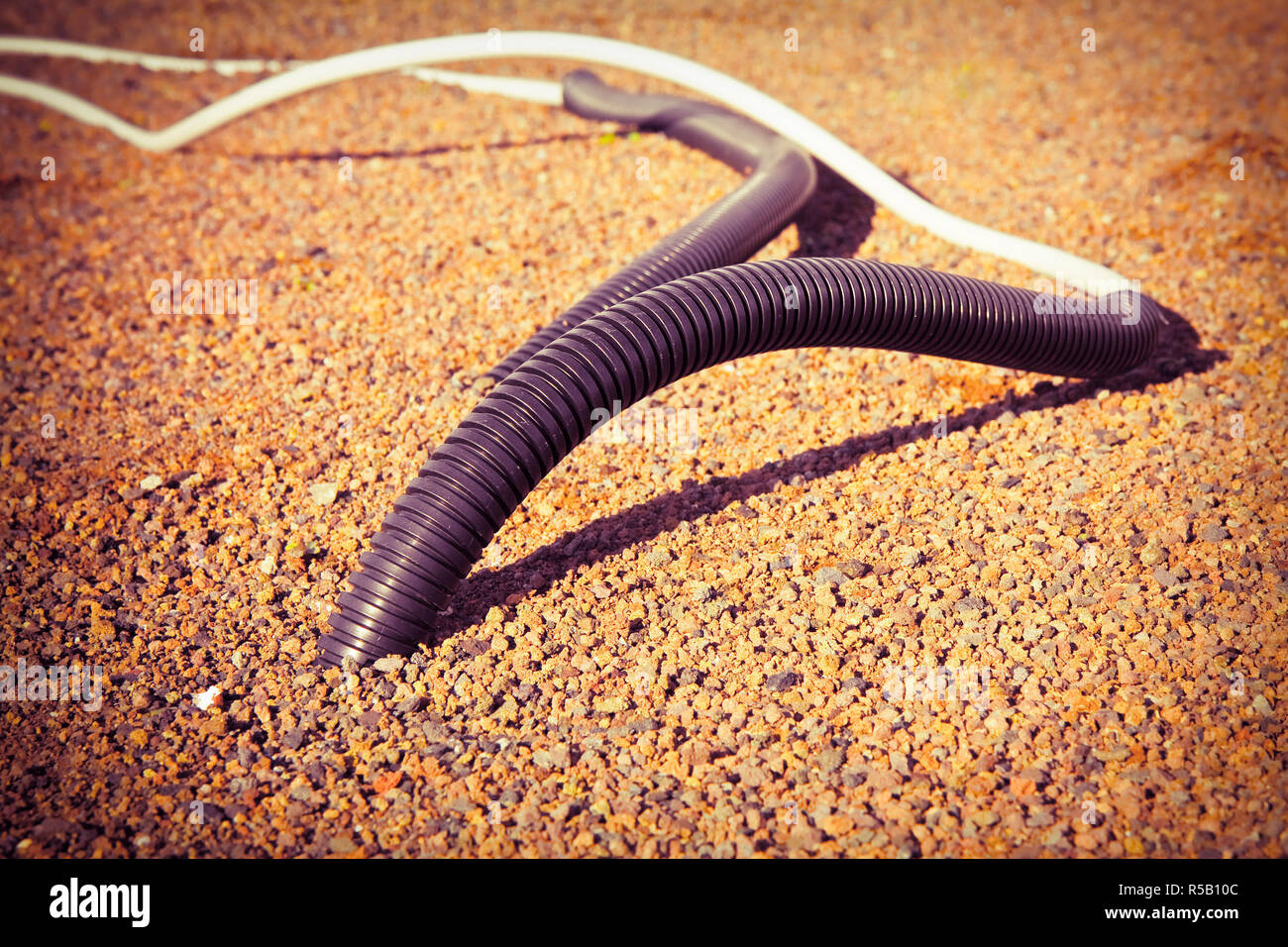 Corrugated pipe with cable coming out from the ground Stock Photo - Alamy