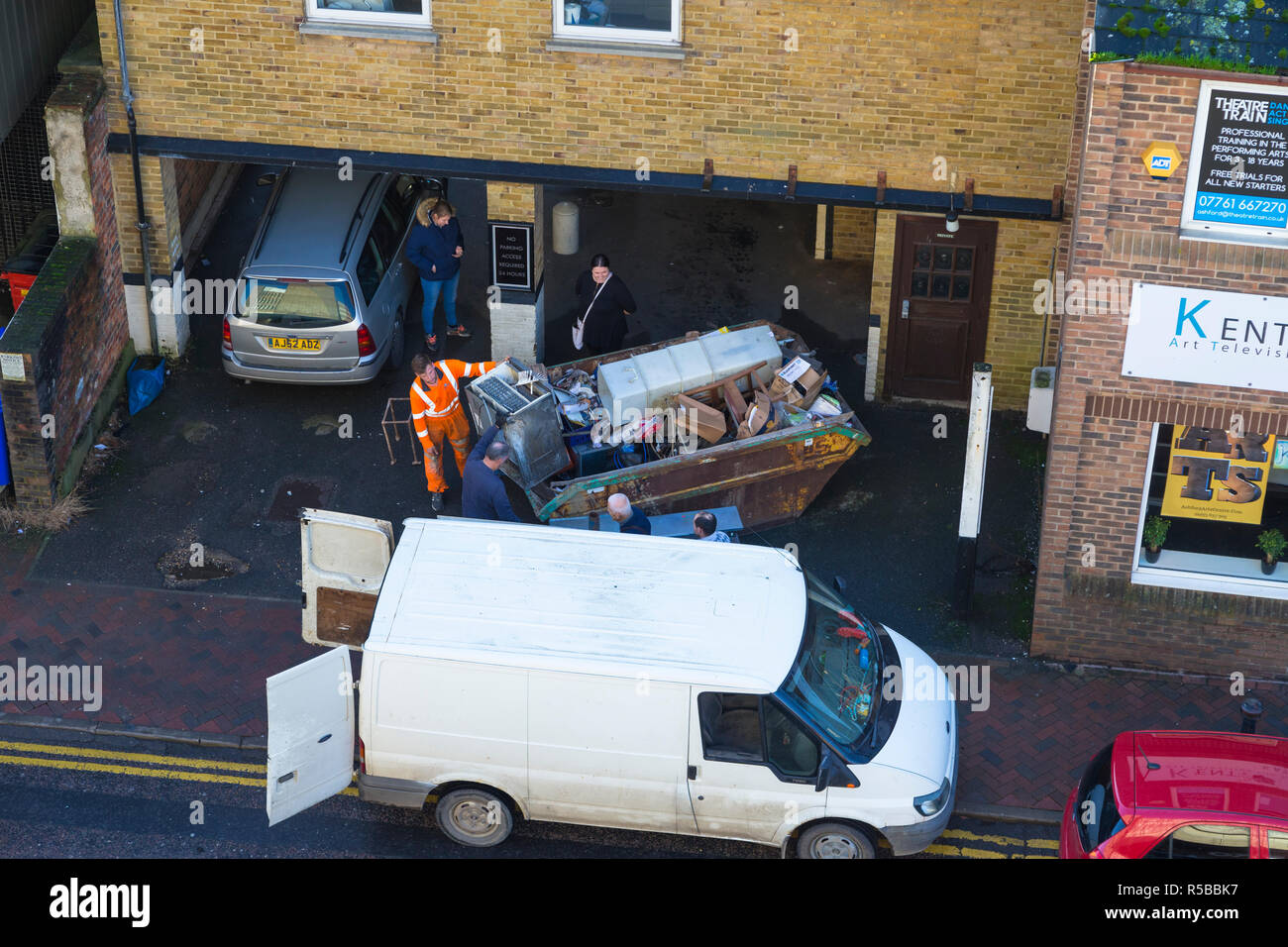People picking through the contents of a skip taking waste metal out ...