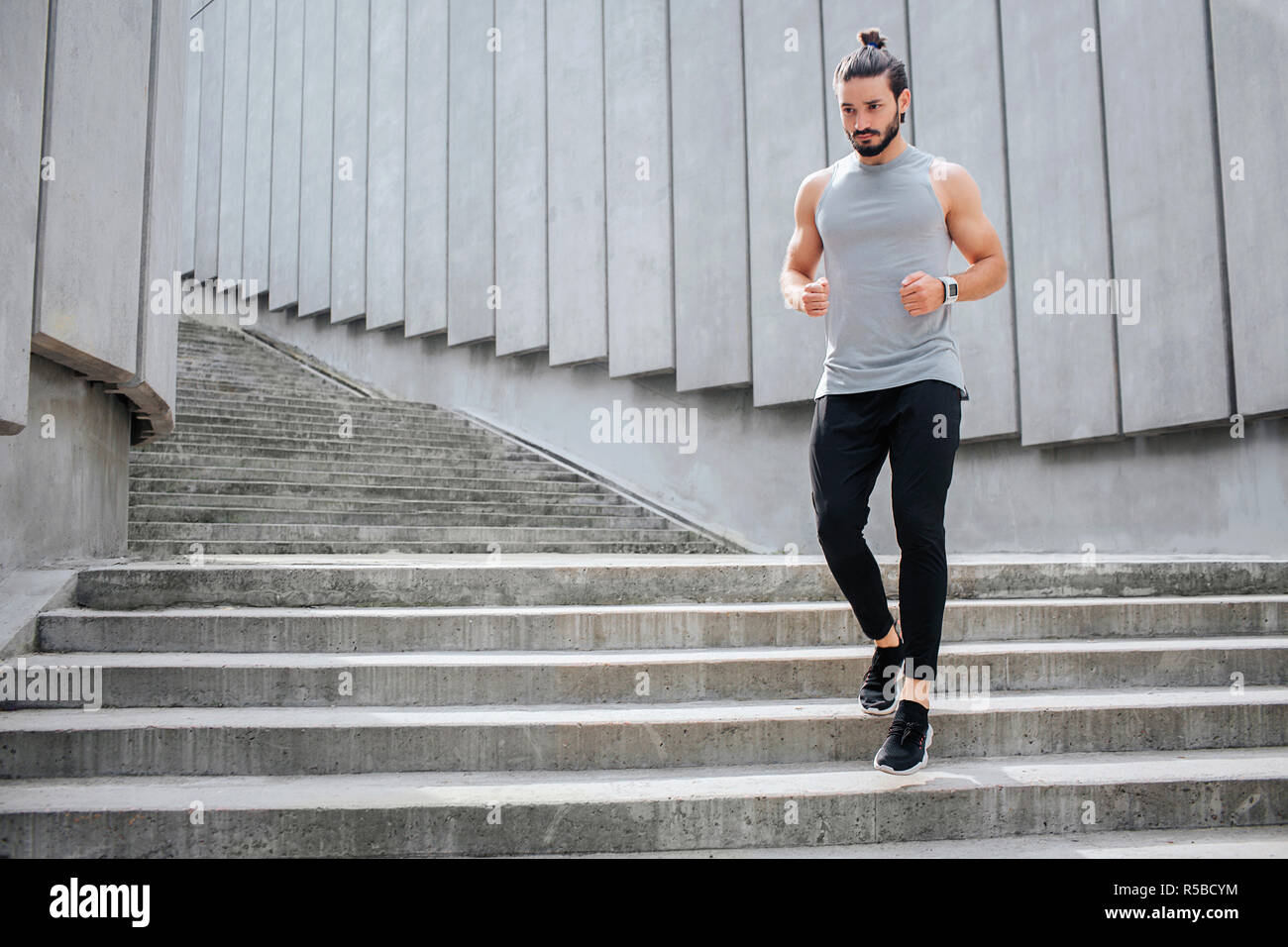 Young man jogging. He runs down on steps. Muscular and well-built man ...