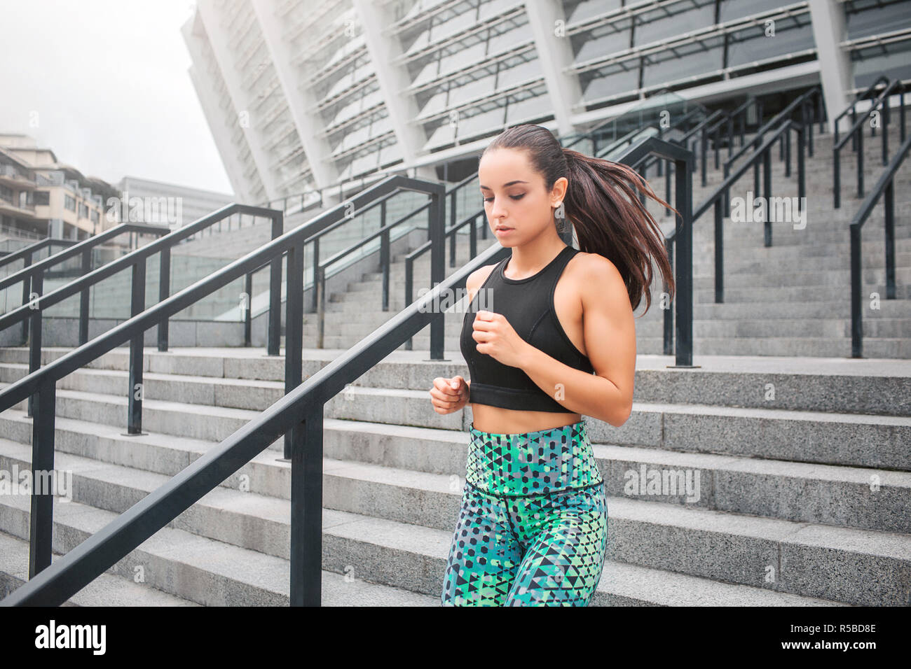 Horizontal portrait of well-buil and beautiful model jogging down steps ...