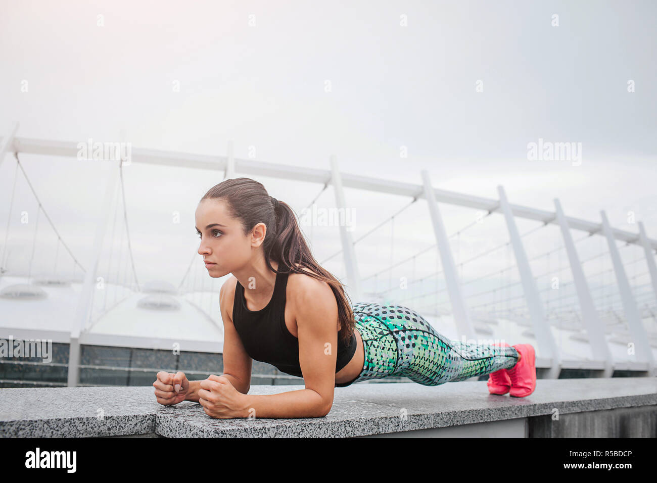 Serious and concentrated young woman stands in plank position and looks ...