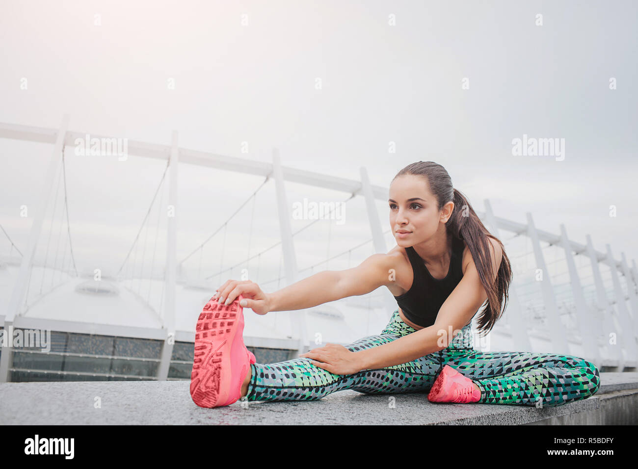Quiet and concentrated young woman stratches her body. She leans to one ...