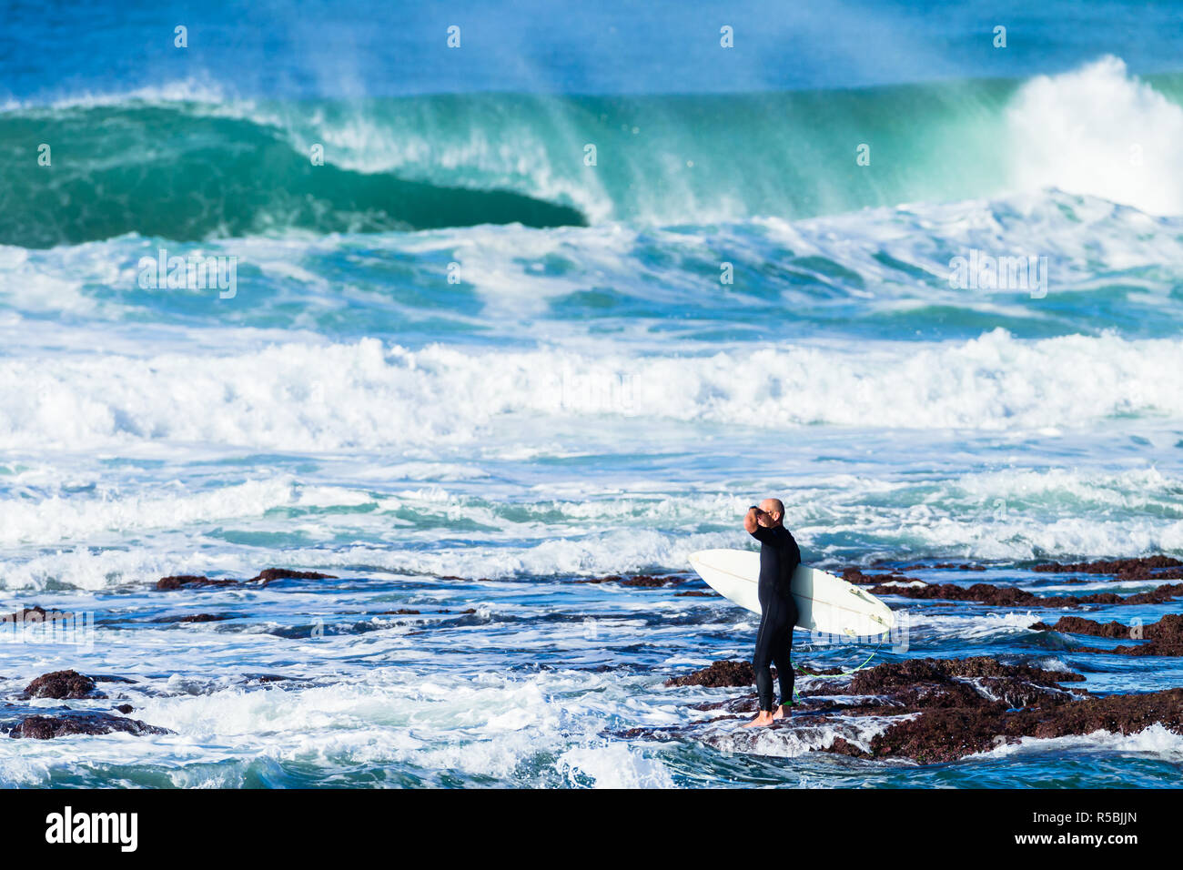 Surfer about to jump into ocean wave doing a rock entry into water to ...