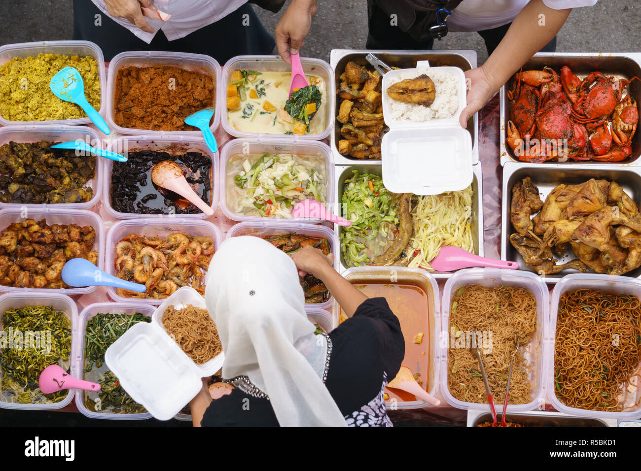 Overhead shot of people buying food over variety of delicious Malaysian ...