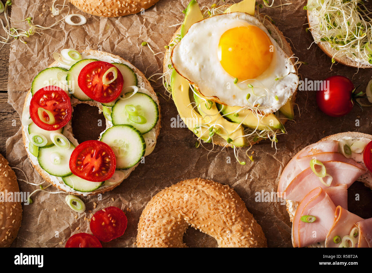 variety of sandwiches on bagels: egg, avocado, ham, tomato, soft cheese ...