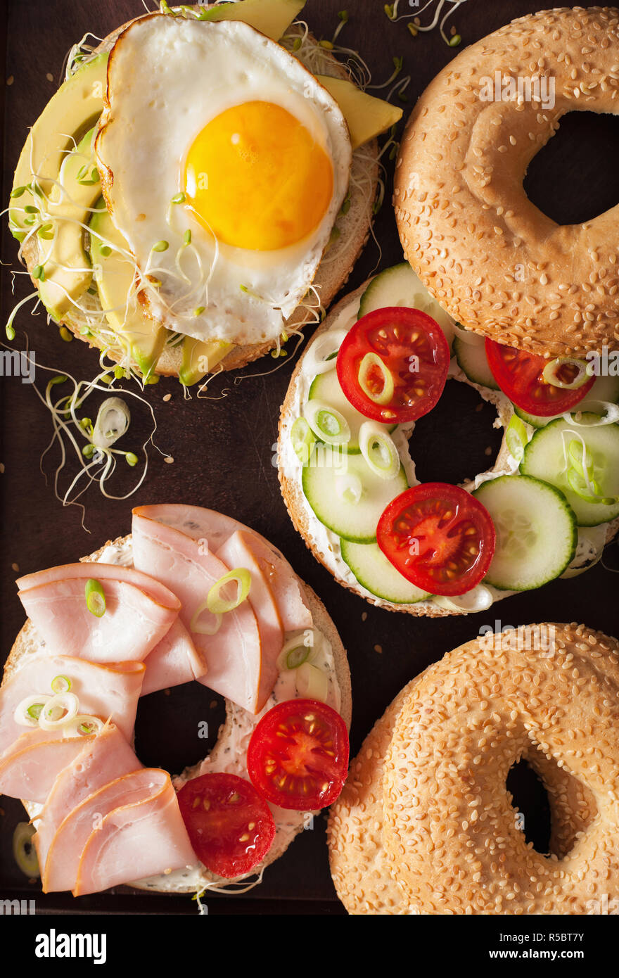 variety of sandwiches on bagels: egg, avocado, ham, tomato, soft cheese ...