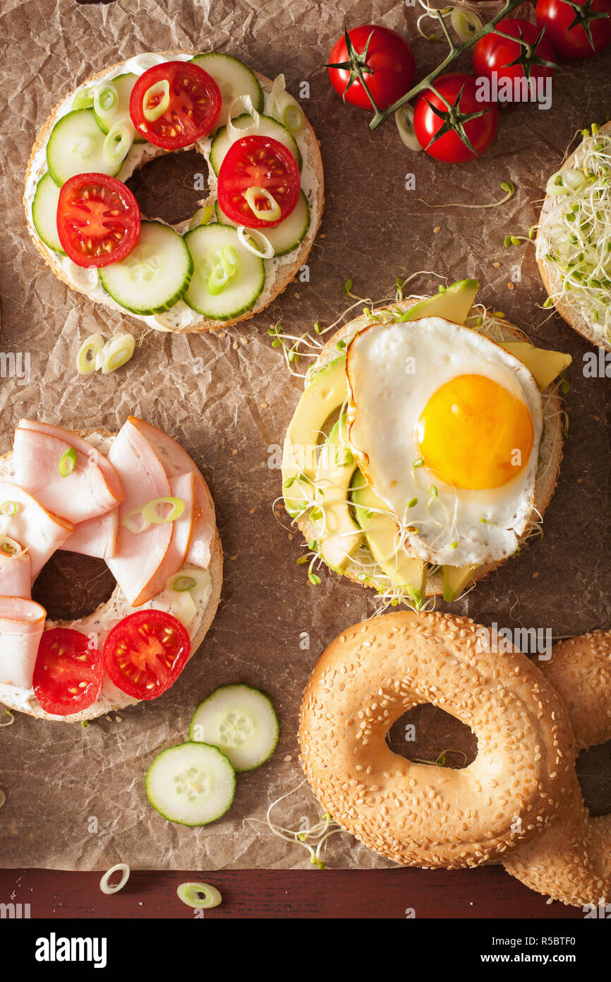 variety of sandwiches on bagels: egg, avocado, ham, tomato, soft cheese ...