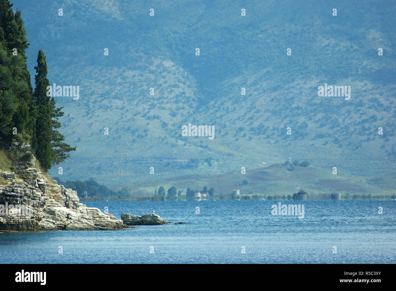 View across a pretty bay with pine clad cliffs. The beautiful Greek ...