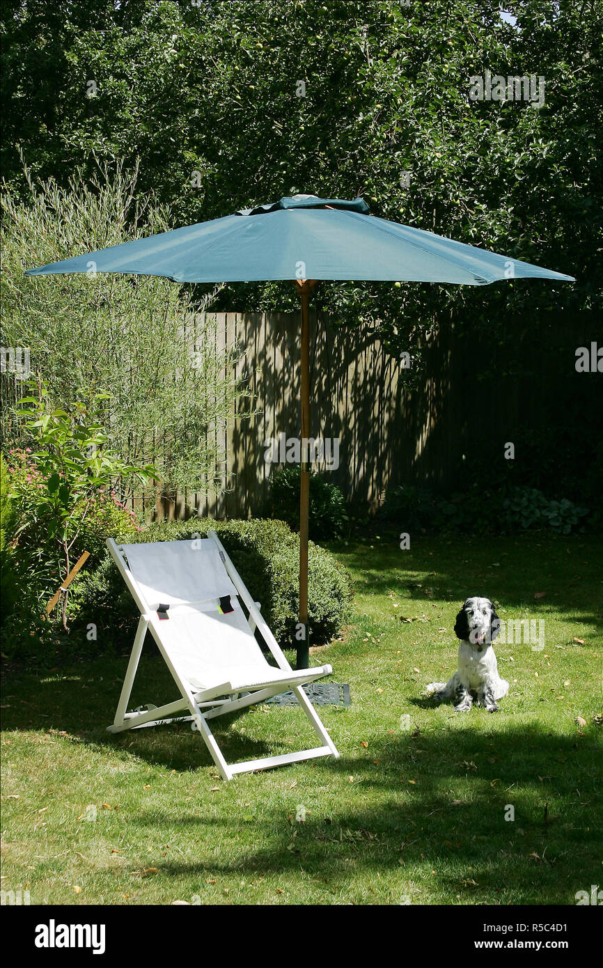 A deck chair and sunshade / parasol in a garden on a summer day Stock ...