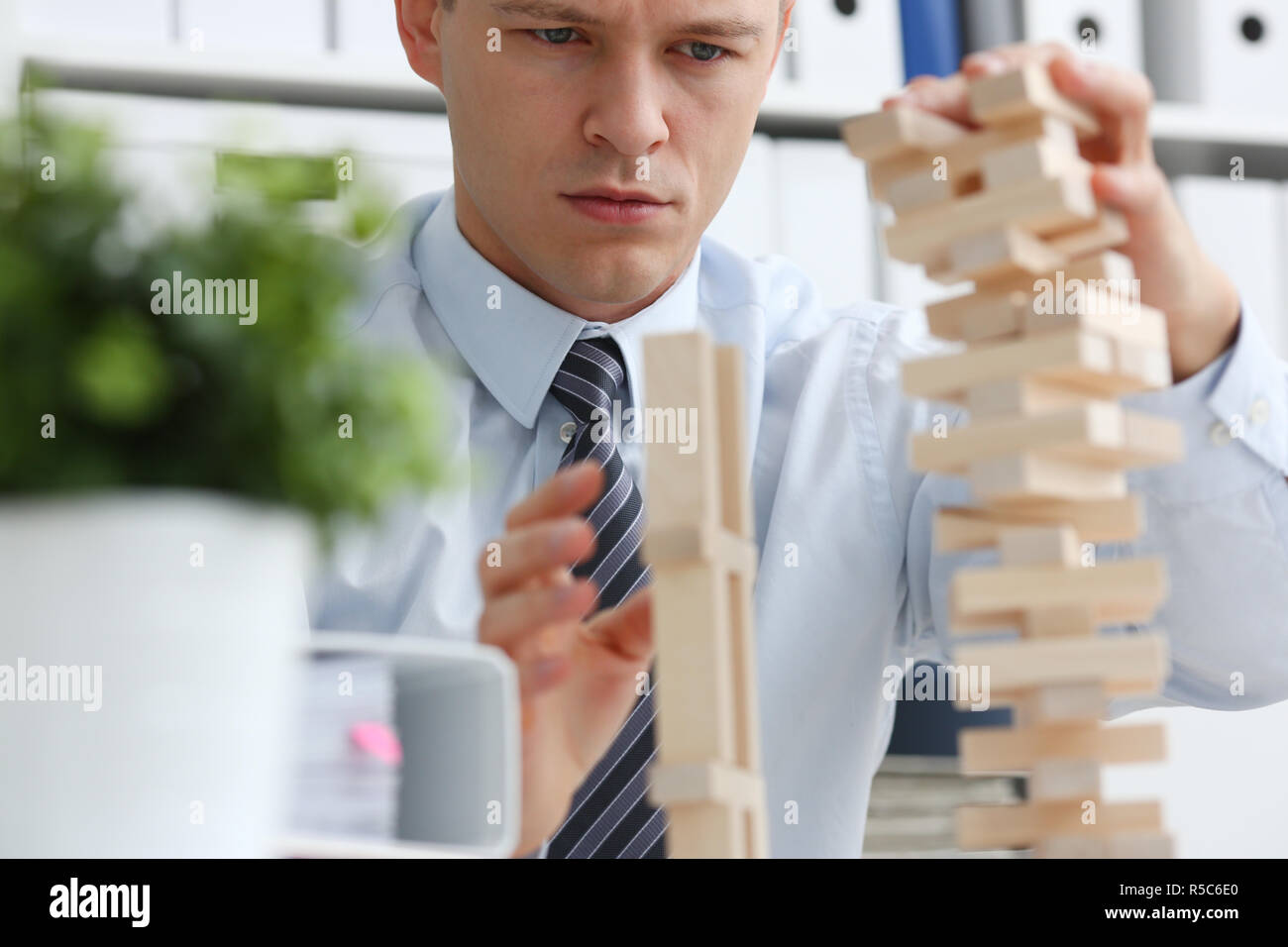 Businessman plays in a strategy of jenga hand Stock Photo - Alamy