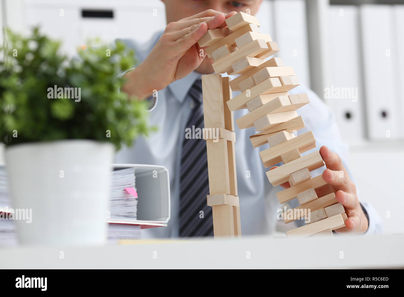 Businessman plays in a strategy of jenga hand Stock Photo - Alamy