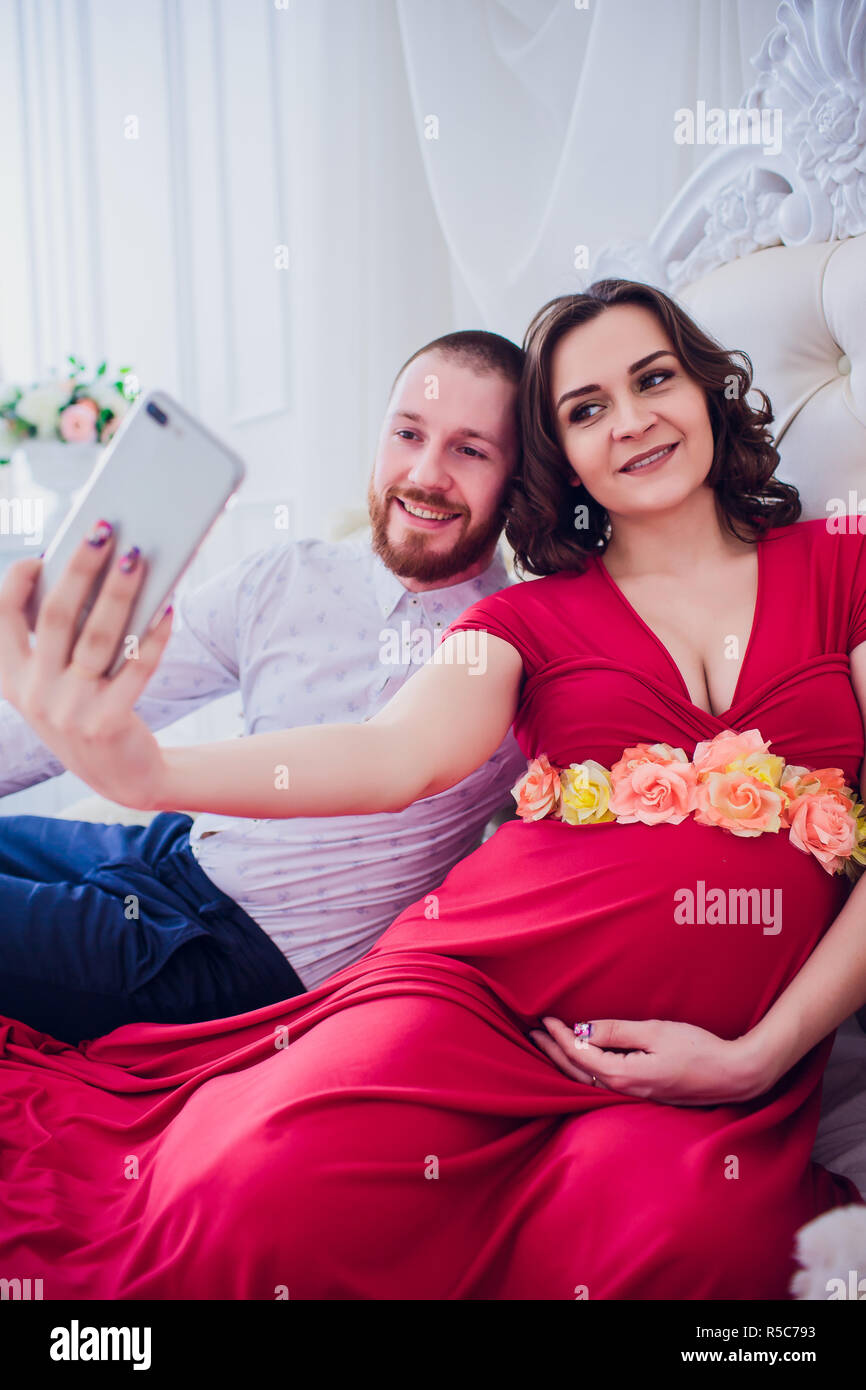 A Husband And A Pregnant Wife Make Selfie Sitting On The Couch They