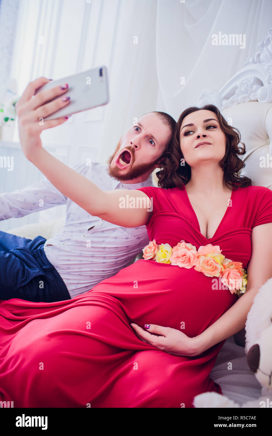 A Husband And A Pregnant Wife Make Selfie Sitting On The Couch They