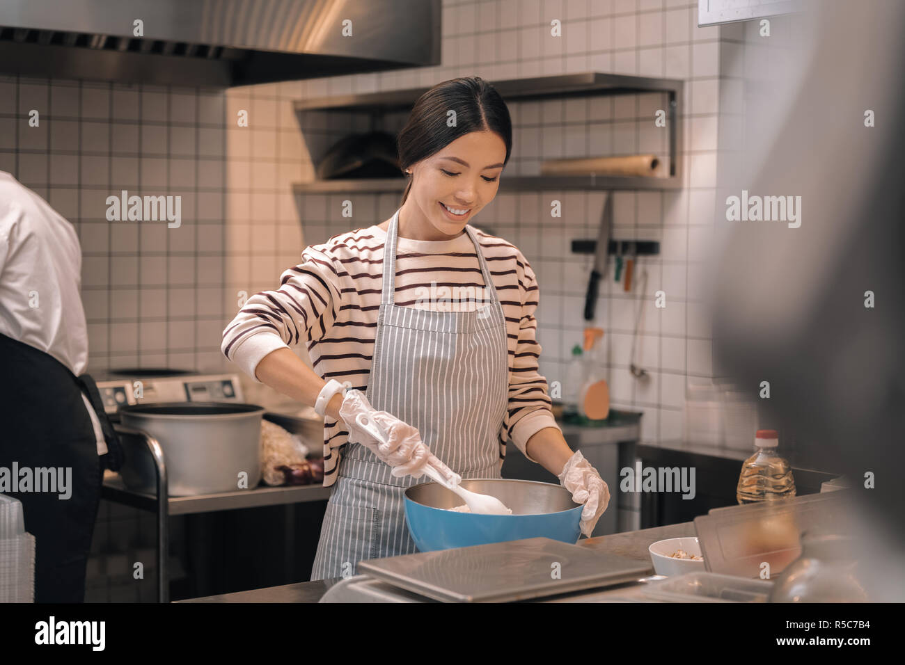 Helpful worker of restaurant helping chef cooking in kitchen Stock ...