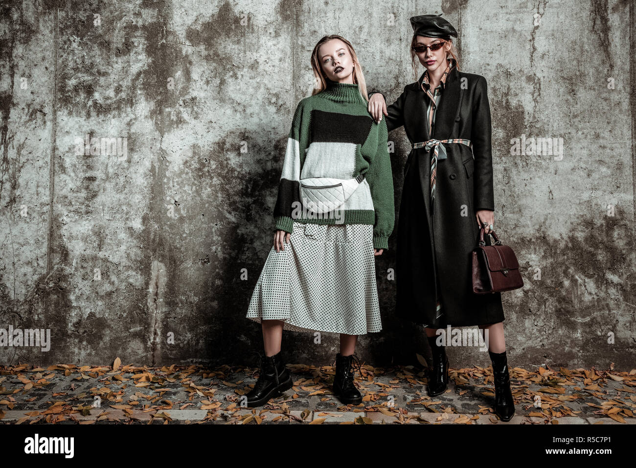 Photo models. Two trendy appealing slim photo models posing near grey ...