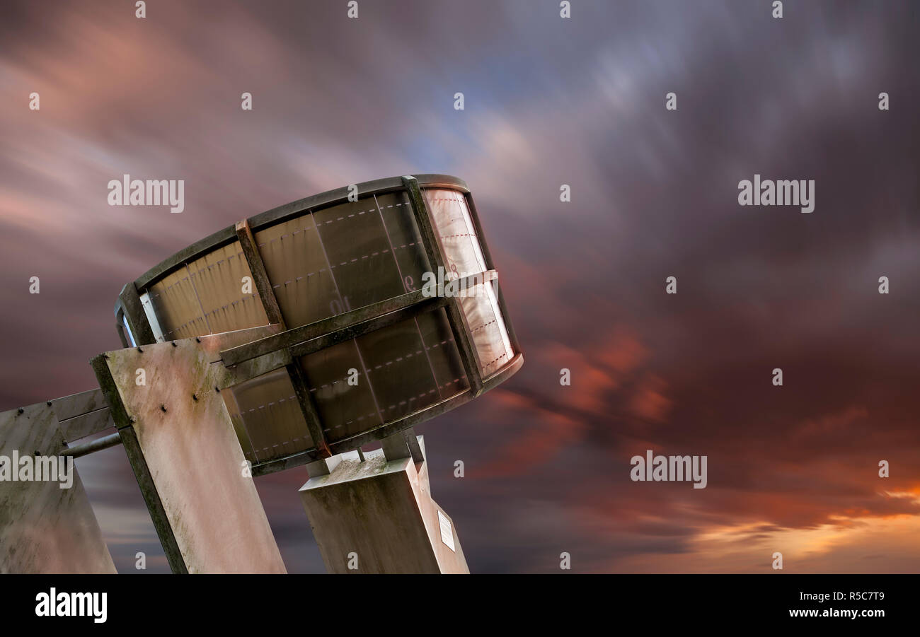 modern sundial outdoors built in metal under a cloudy sky at sunset ...