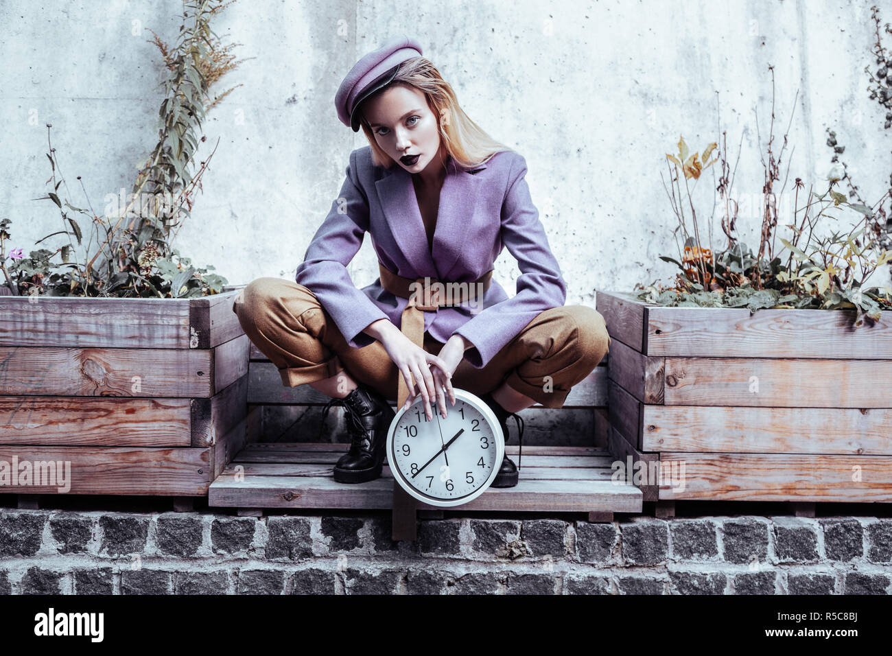 Pose with clock. Slim glamorous photo model wearing purple jacket ...