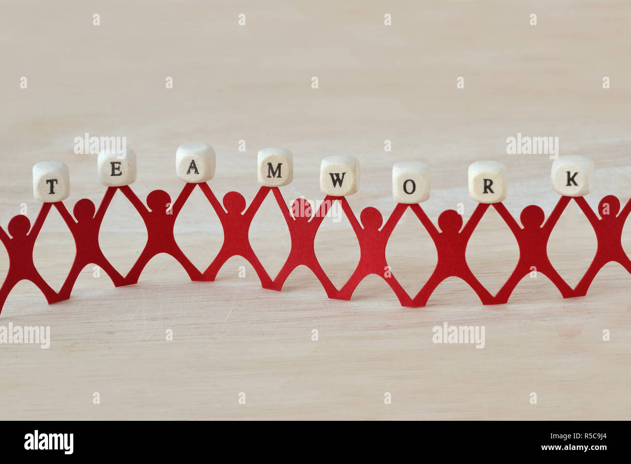 Paper people chain holding Teamwork text written on wooden cubes Stock ...