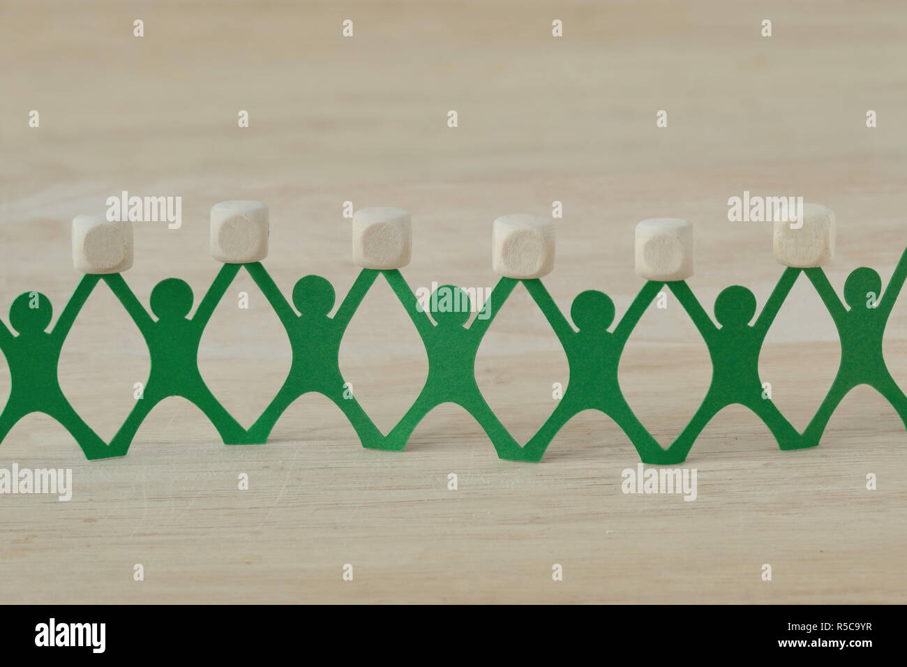 Paper people chain holding blank wooden cubes Stock Photo - Alamy