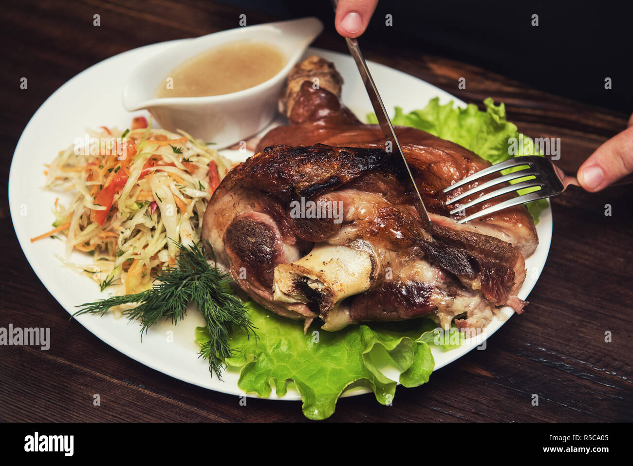Man eats tasty dish of pork shank Stock Photo - Alamy