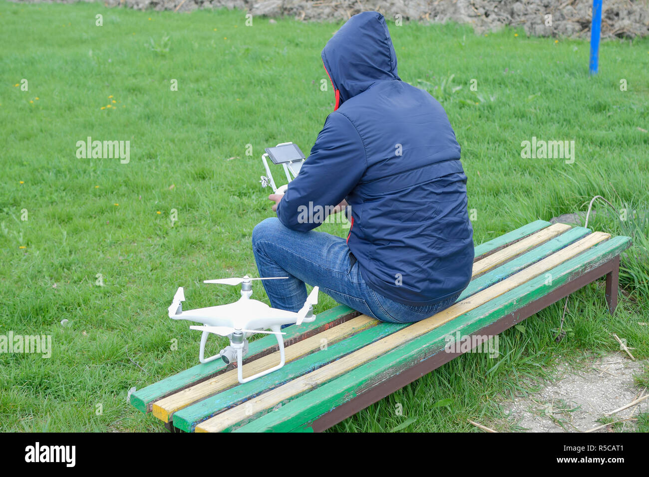 A man with a remote control quadroopter in his hands is sitting on a ...