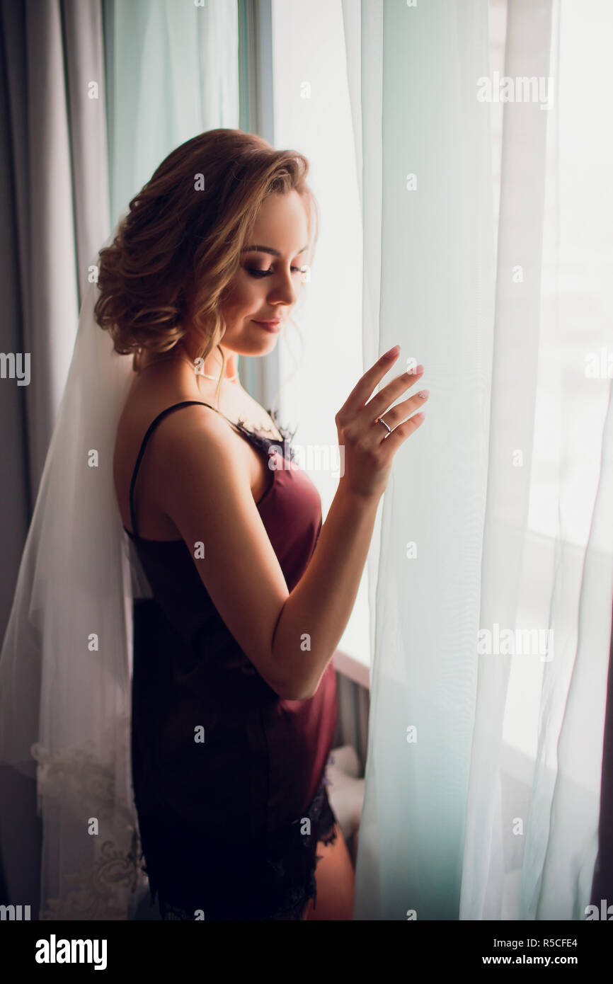 girl in a wedding veil near a window in a dark room green curtains ...