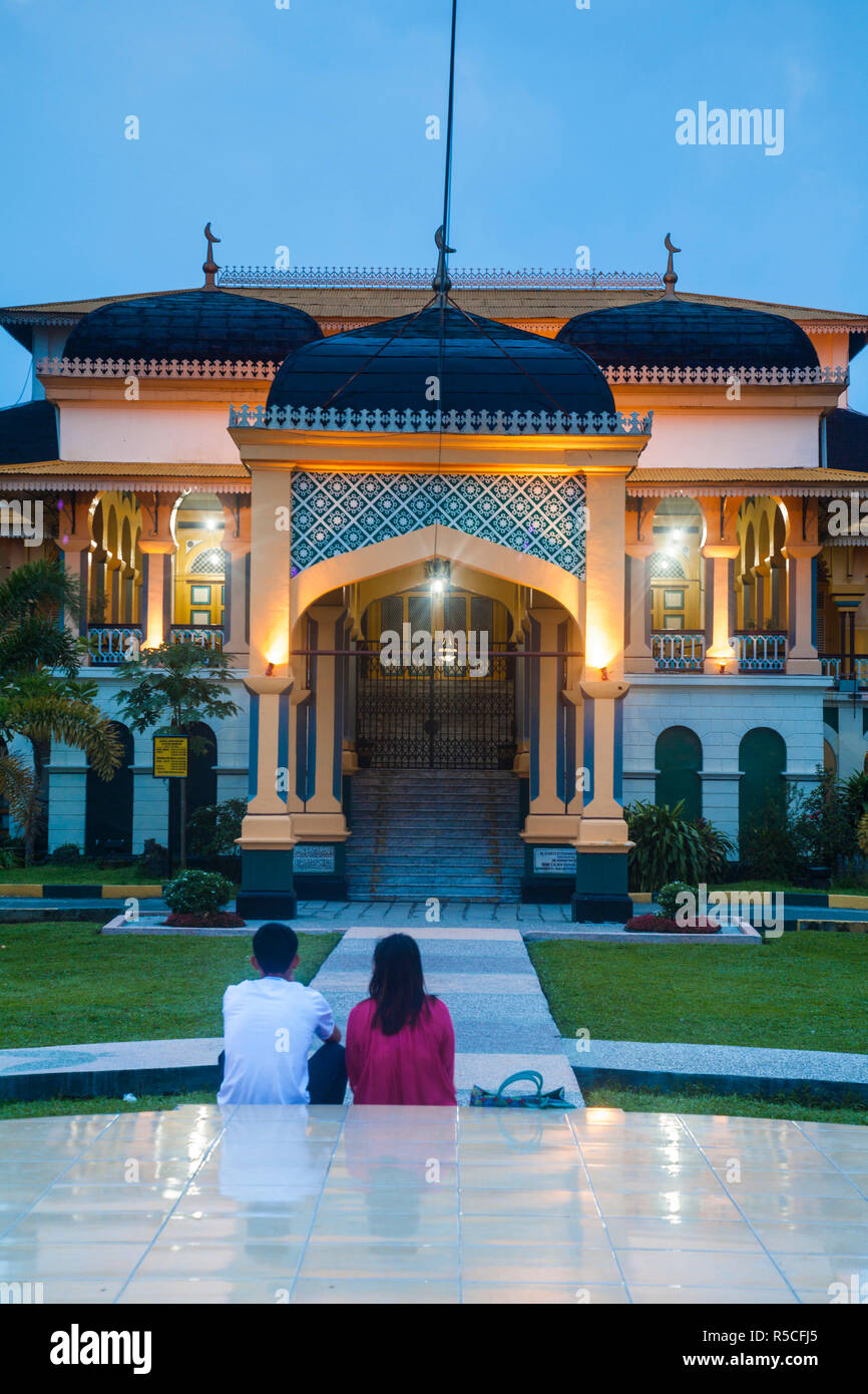 Indonesia, Sumatra, Medan, Couple sitting looking at Maimoon Palace ...