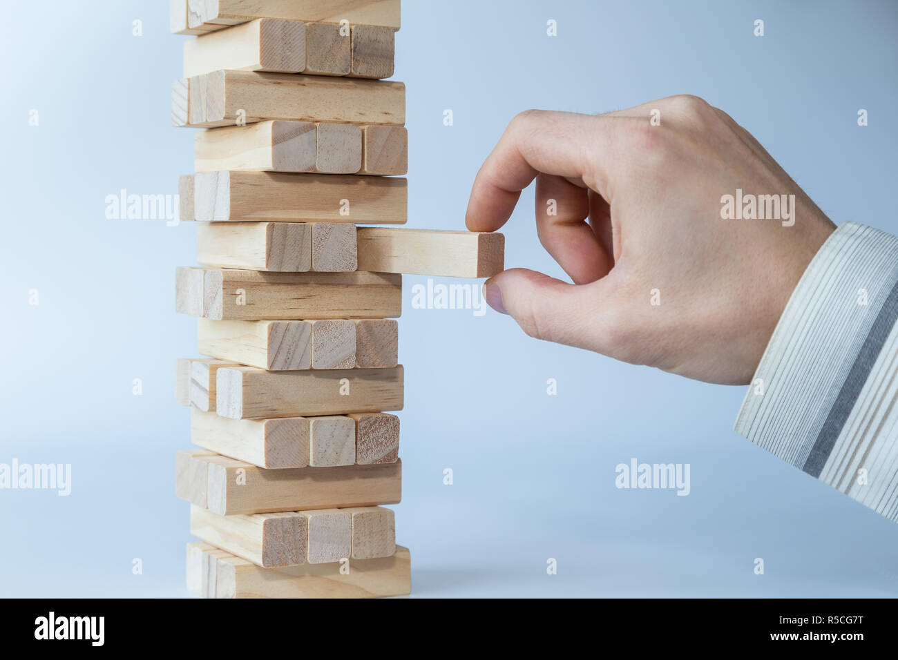 Businessman taking first block or putting last block to a sturdy tower ...