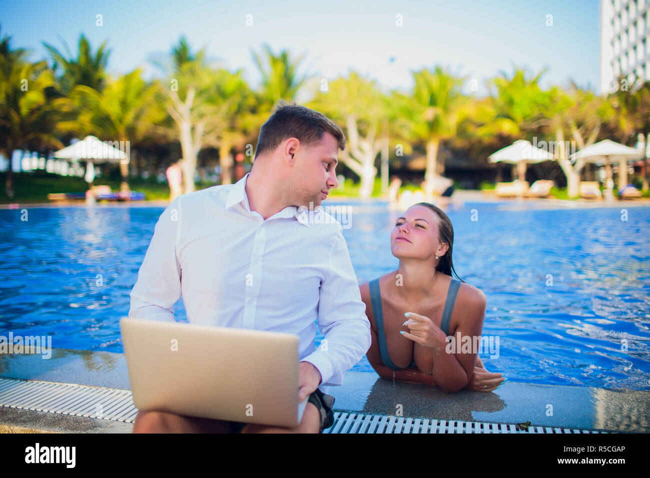 woman female distracting from the work of a freelancer man on a pool ...