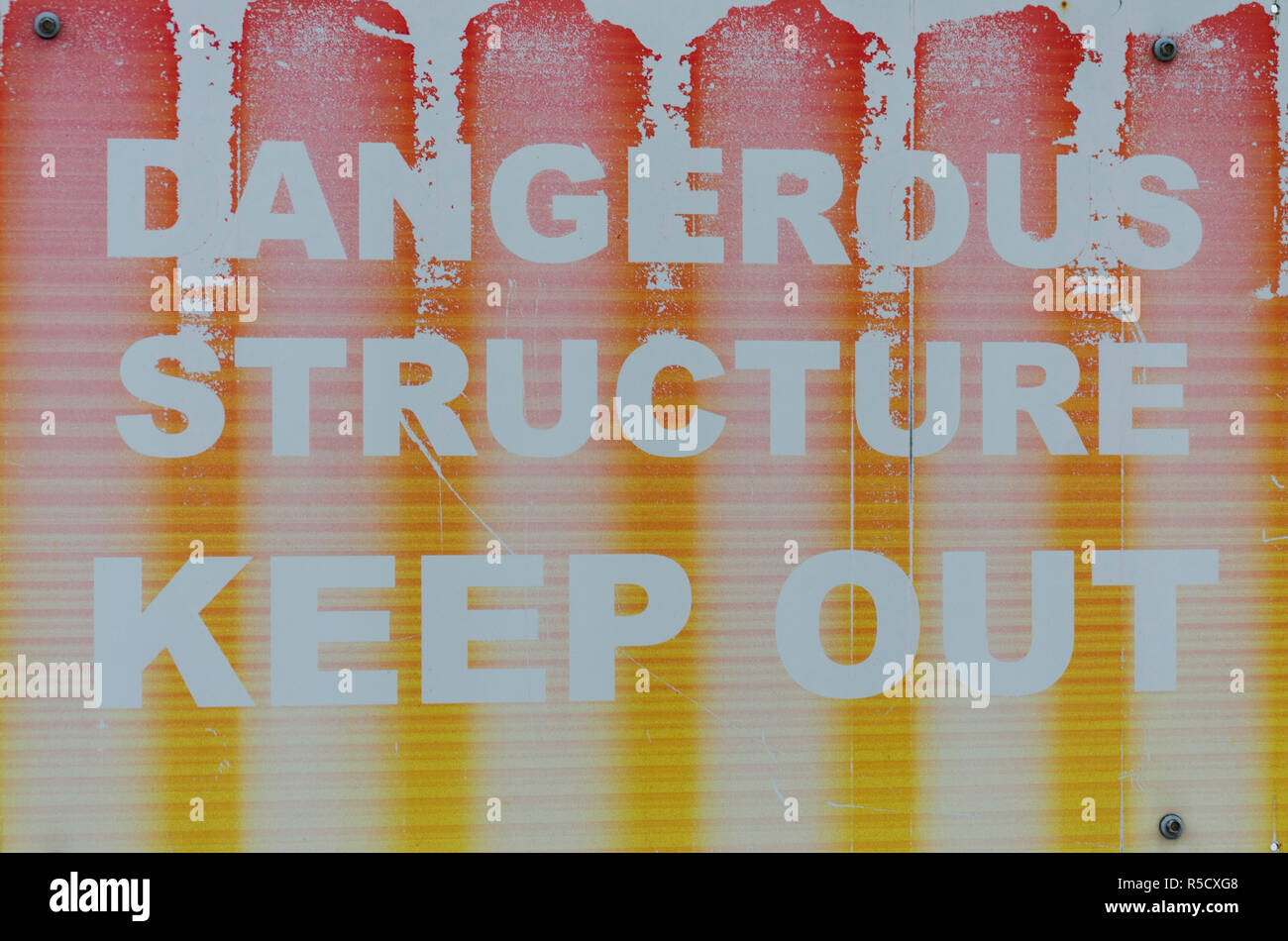 Faded sign warning of a dangerous structure Stock Photo - Alamy