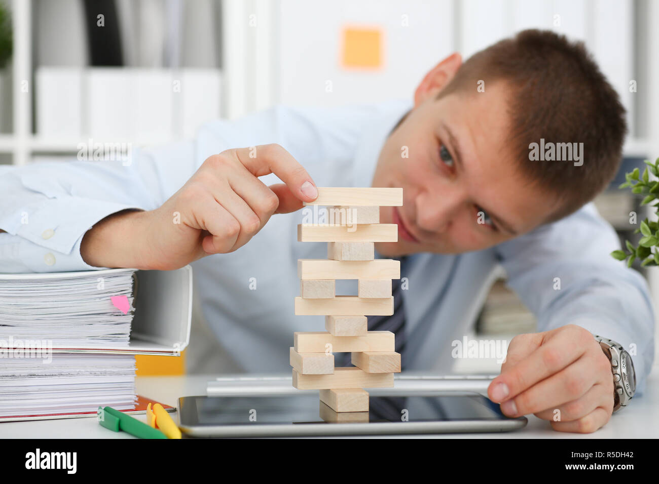 Businessman plays in a strategy of jenga hand Stock Photo - Alamy