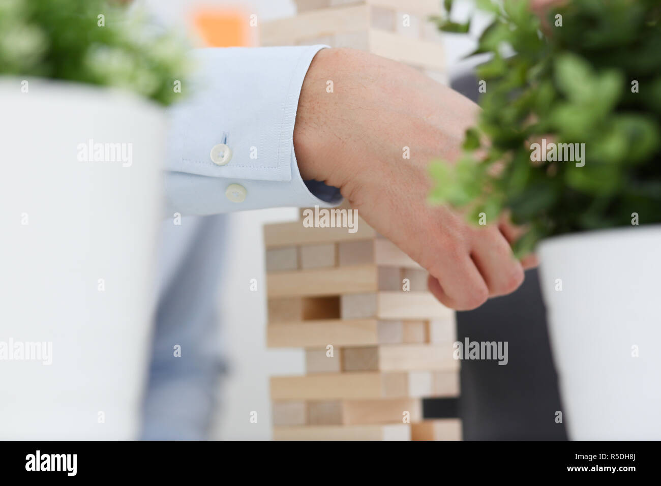 Businessman plays in a strategy of jenga hand Stock Photo - Alamy