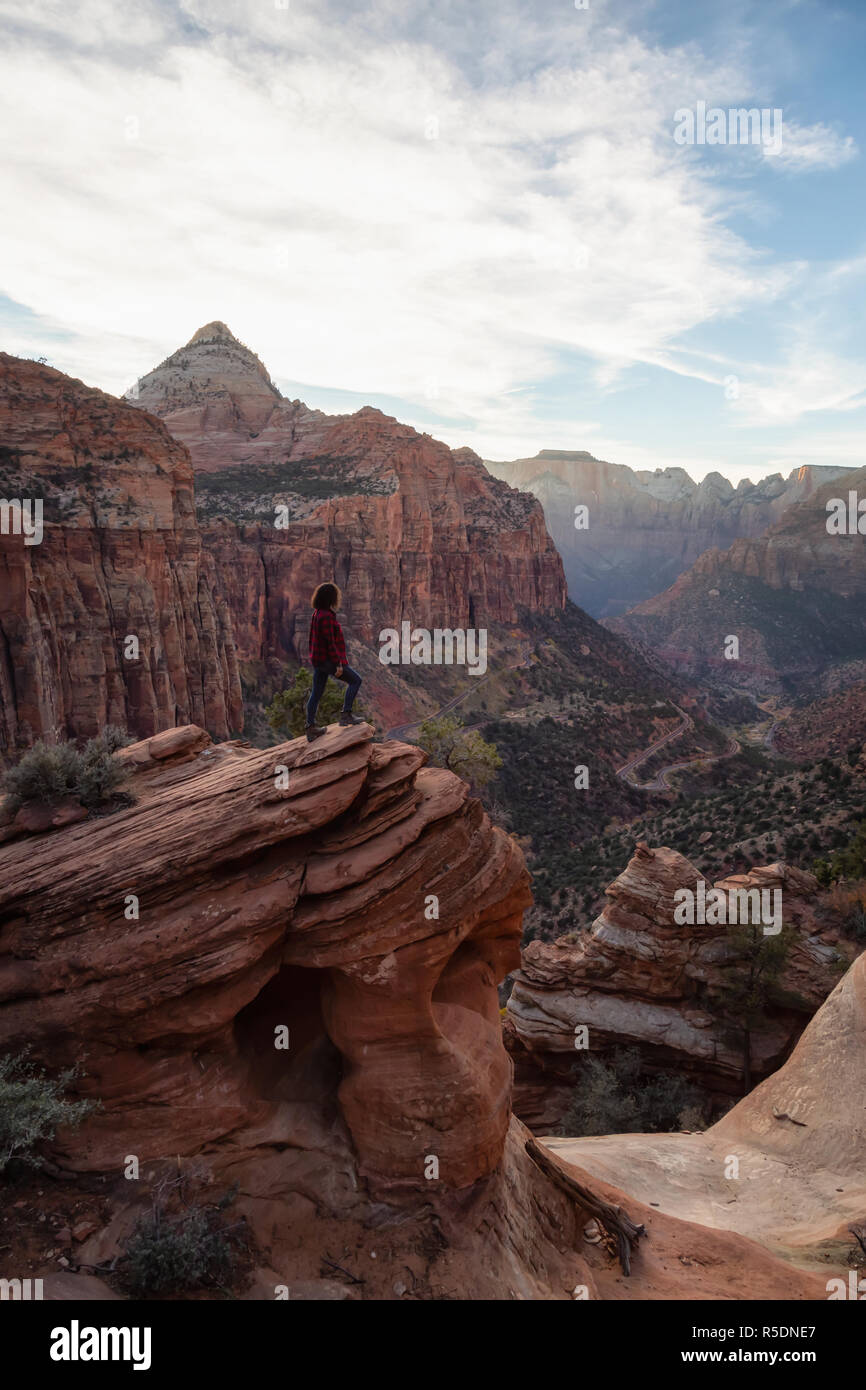 Adventurous Girl at the edge of a cliff is looking at a beautiful ...
