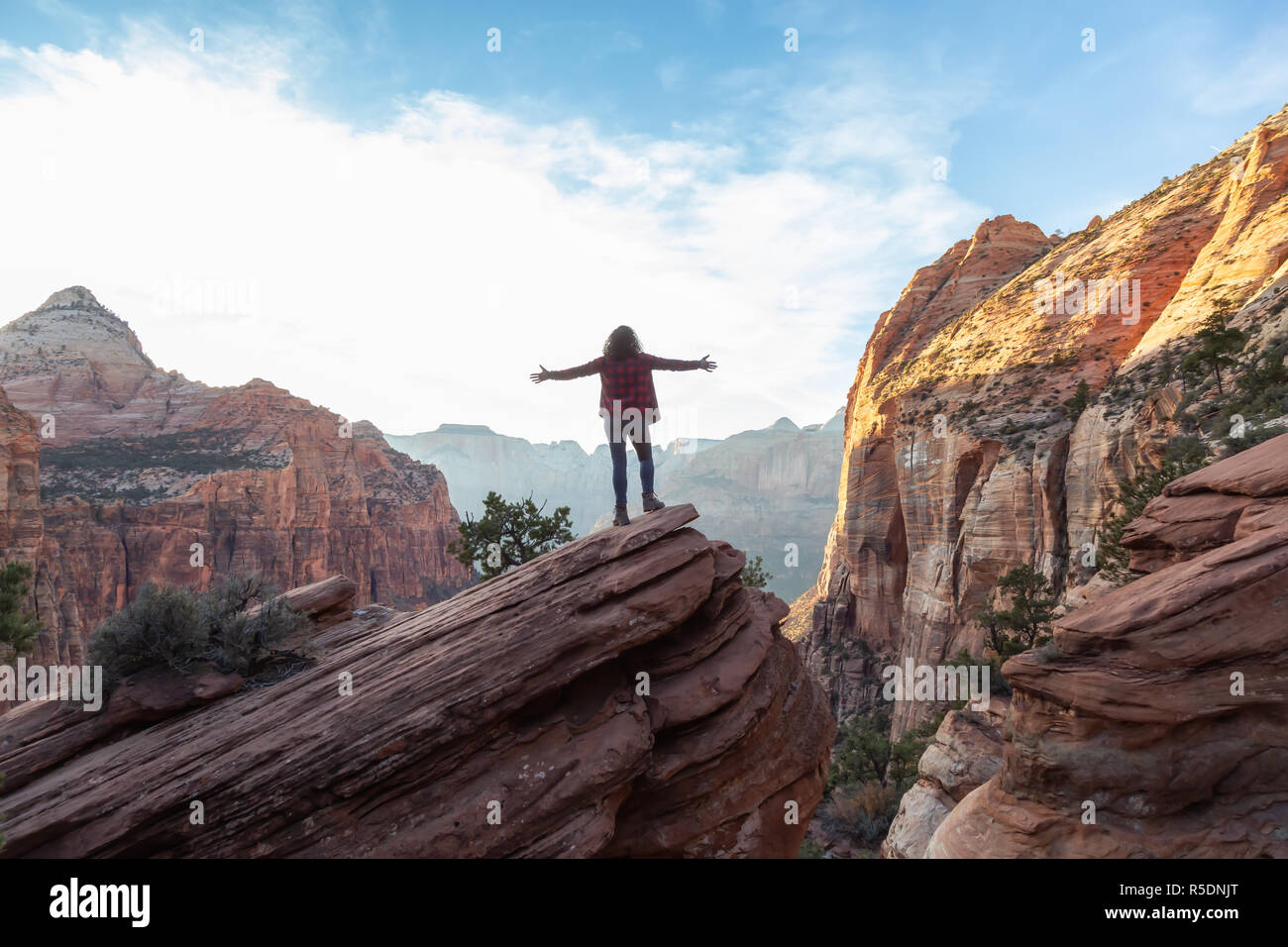 Adventurous Girl at the edge of a cliff is looking at a beautiful ...