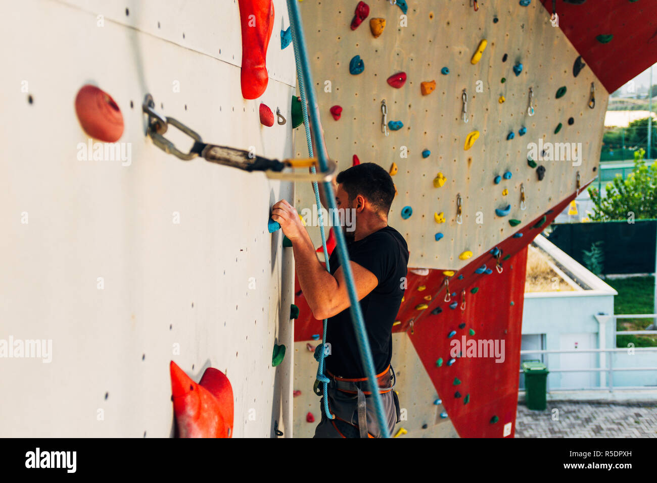 Young climber guy climbing on practical rock in climbing center ...