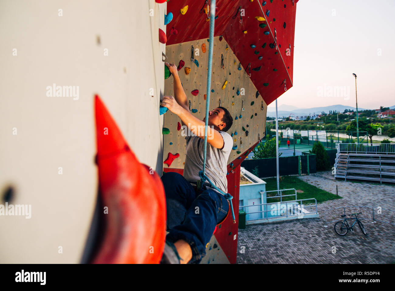 Young climber guy climbing on practical rock in climbing center ...