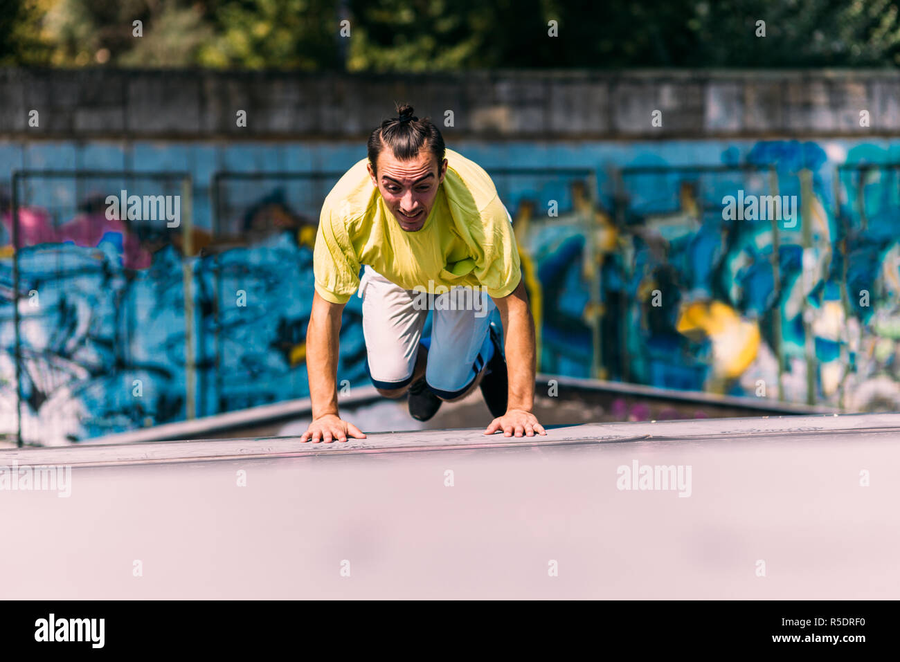 Training day of a young parkour man jumping over obstacles in skatepark ...