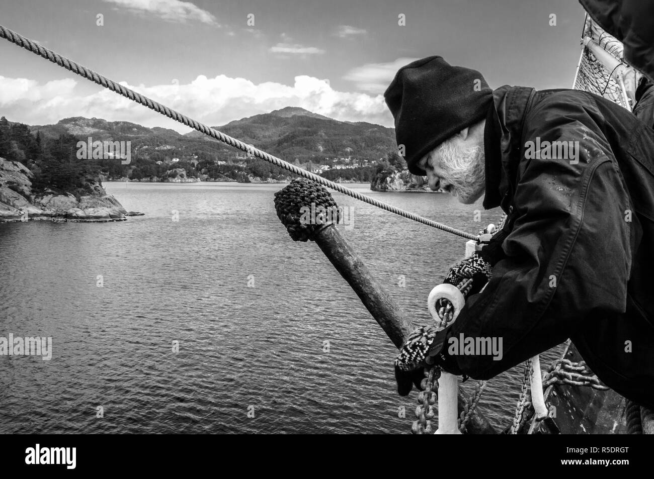 A black and white photo of a sailor looking overboard on a ship with ...