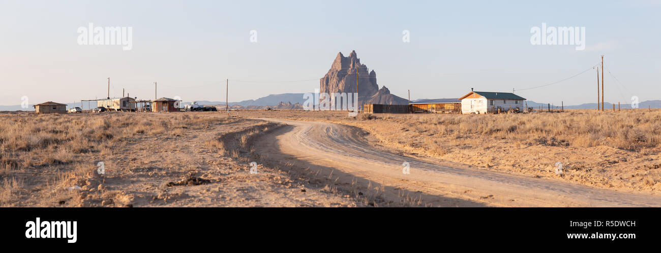 View of an old house in a dry desert with a Shiprock mountain peak in ...