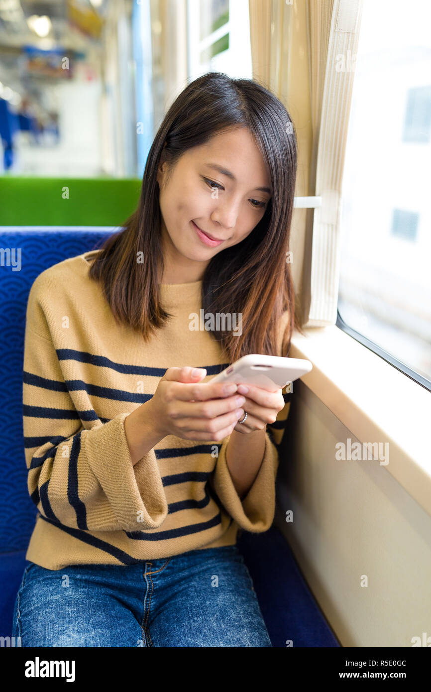 Woman use of mobile phone on train Stock Photo - Alamy