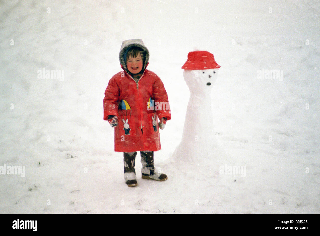 Girl in a red raincoat in the snow. She insisted on going out in a ...