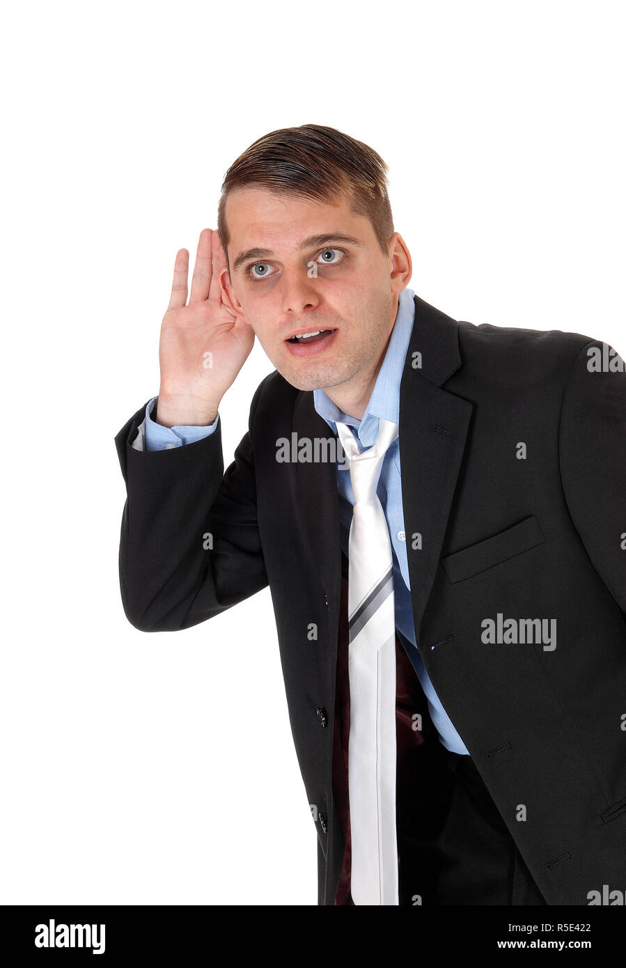 A business man is hard of hearing has his hand behind his ear to hear ...