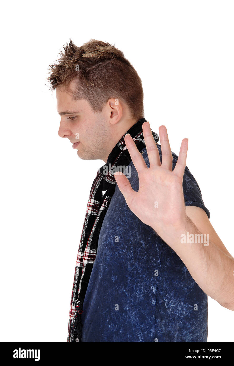 A young man standing in profile holding one hand up and saying NO I do ...