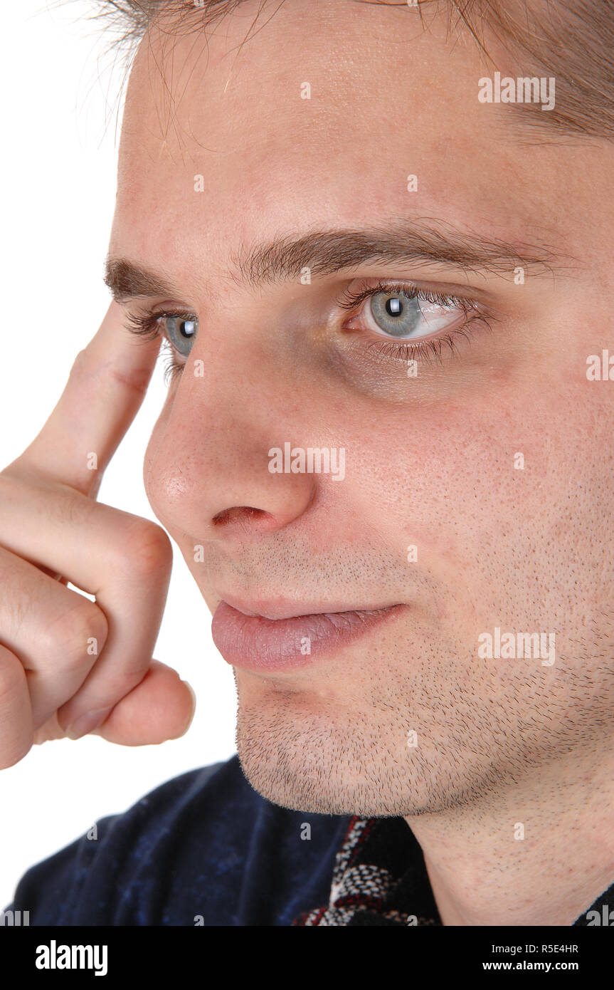 The portrait of a young mans face in a closeup image with one finger on ...